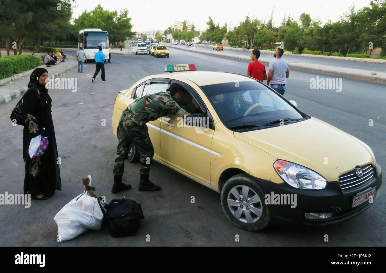 DAMASCUS, Syria - A woman waits for a taxi near a bus terminal in ...