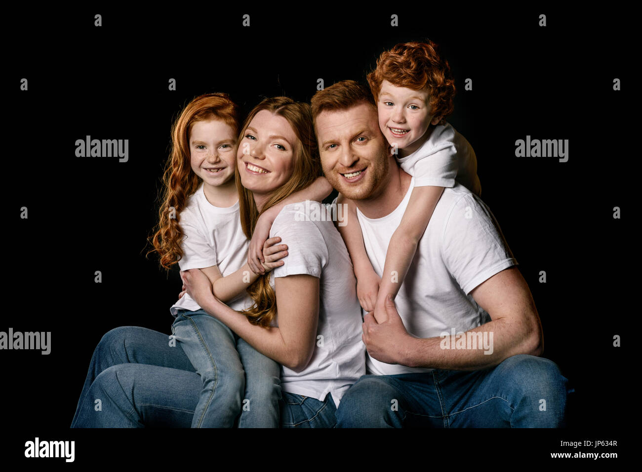 Happy redhead family sitting embracing and smiling at camera isolated ...