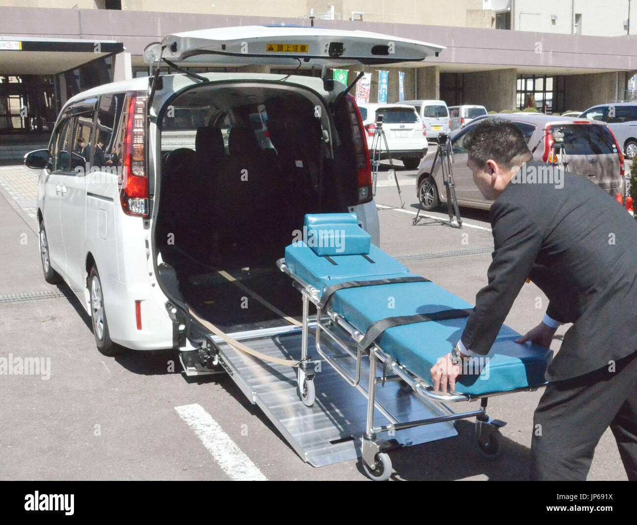 A man pushes a stretcher into a vehicle for carrying disabled people ...