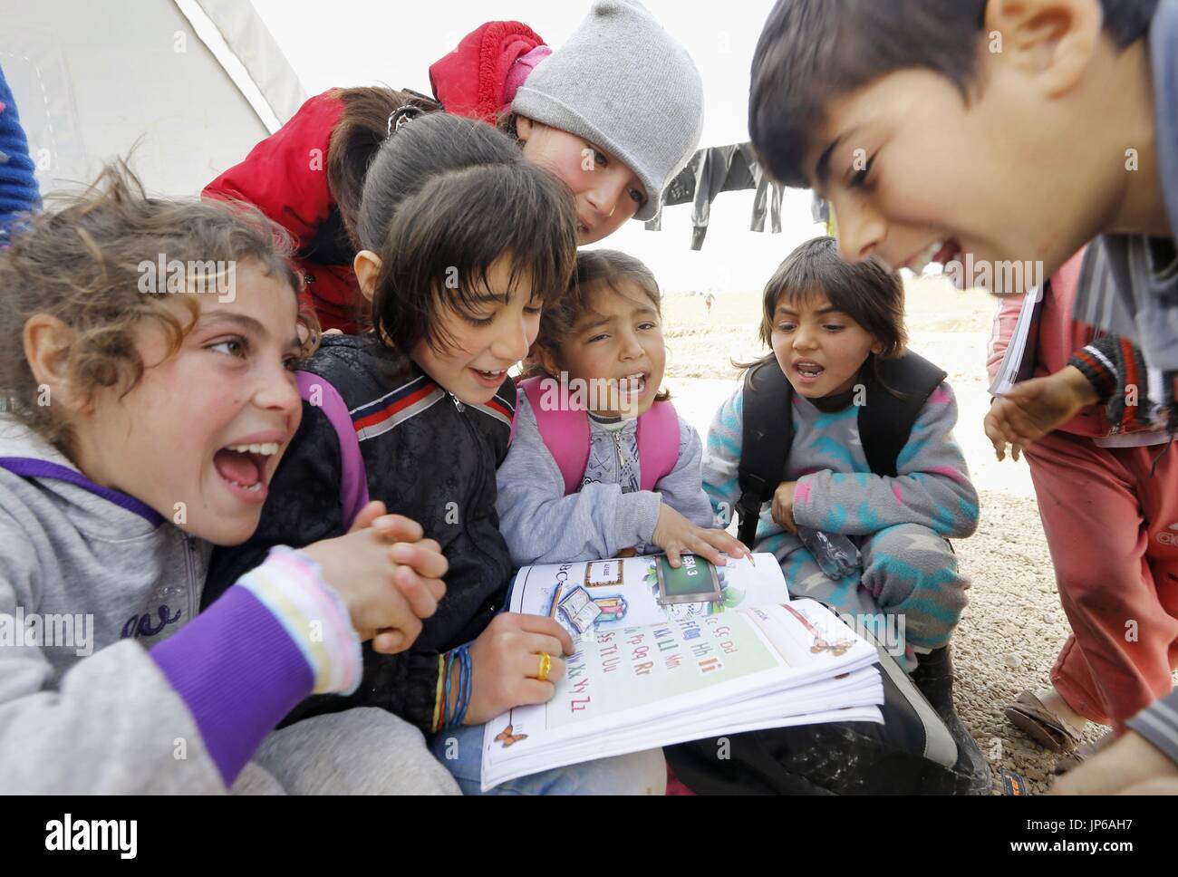 Syrian children cheerfully read aloud a textbook at a refugee camp in ...