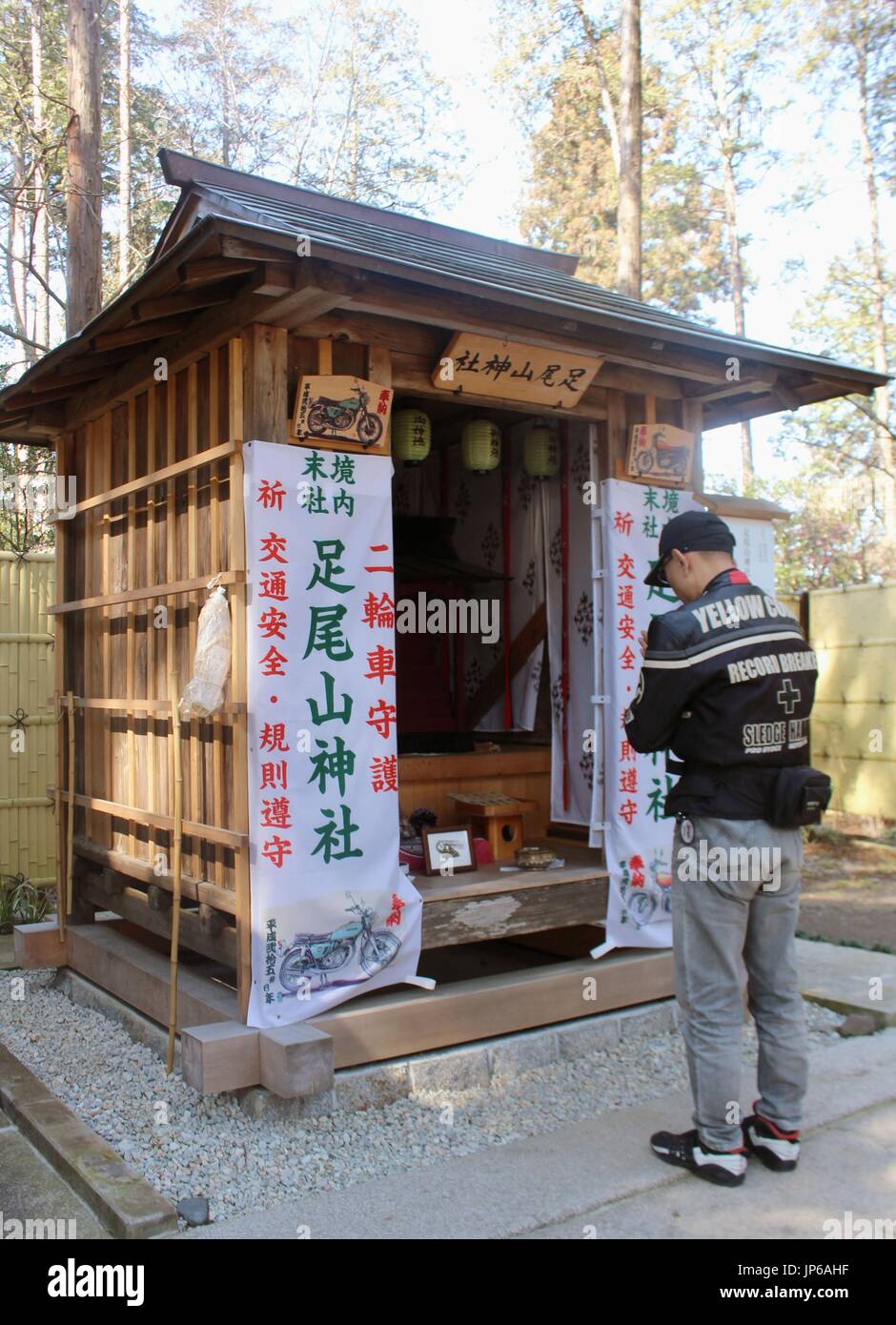 A motorcycle rider offers a prayer for road safety at Mt. Ashio Shrine ...