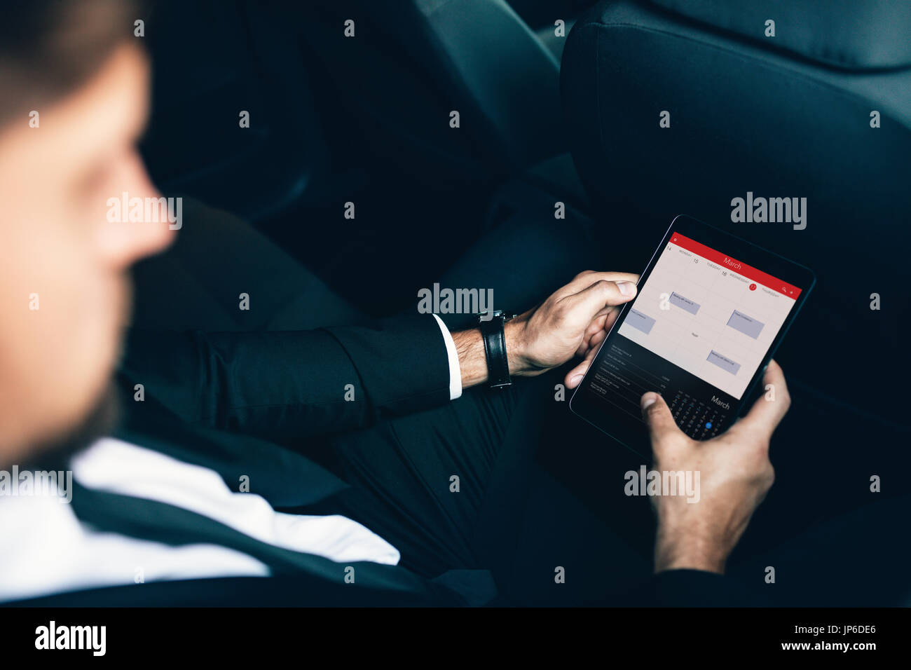 Businessman sitting in car planning and scheduling meetings on his ...