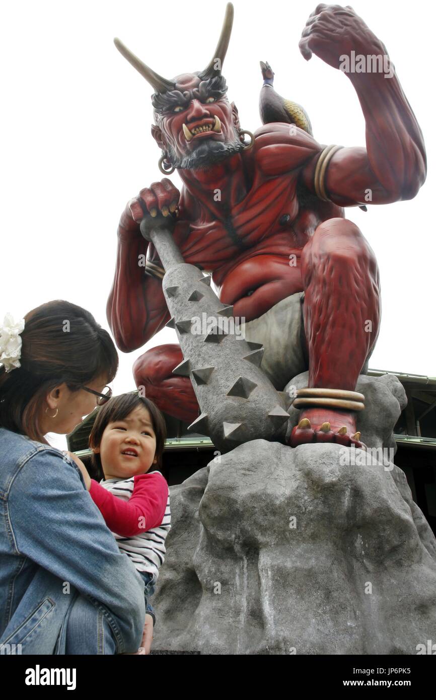 A woman and a child check out a big "oni" demon monument in the town of ...