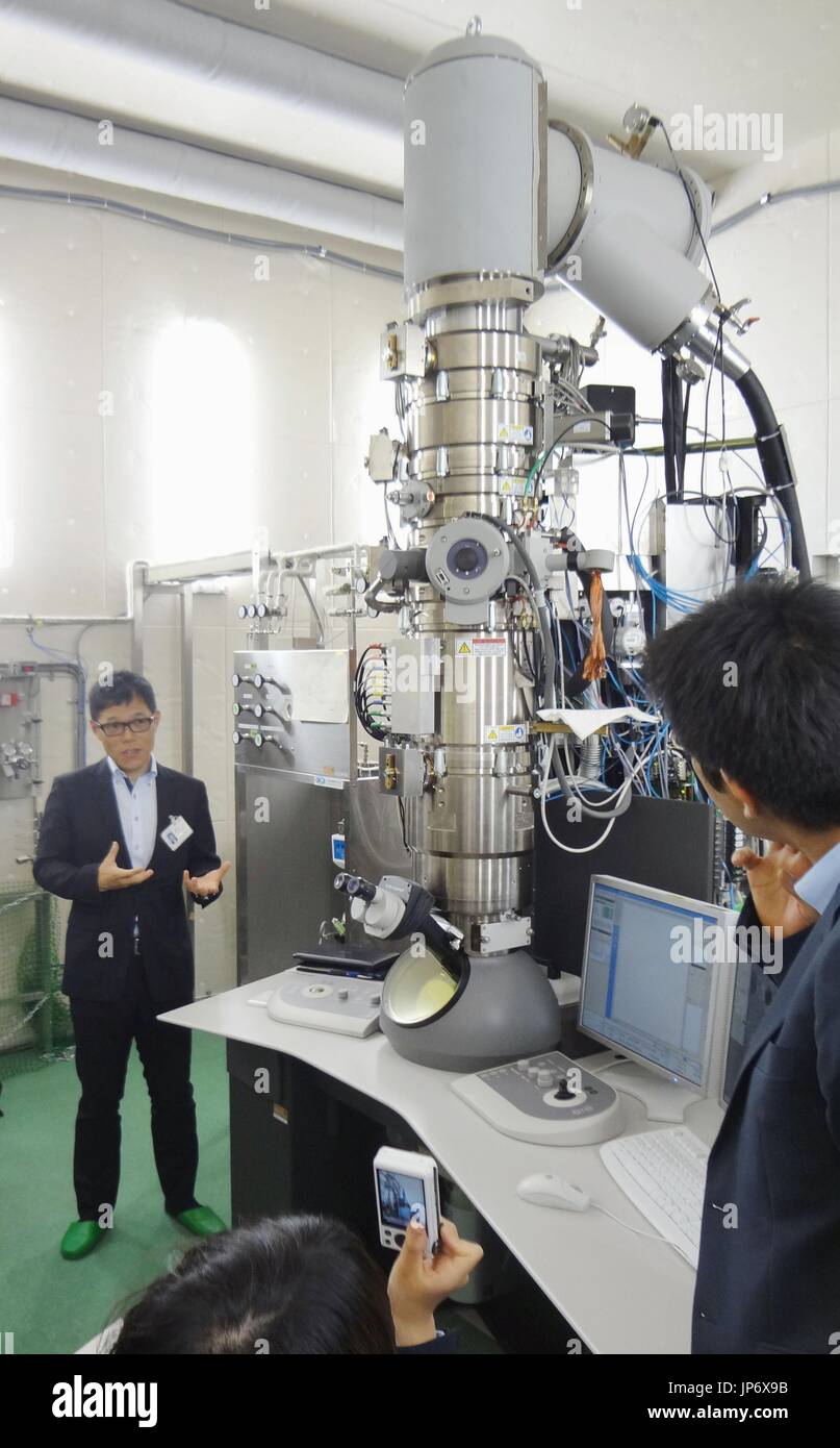 A Toyota Motor Corp. engineer (L), standing next to a transmission electron microscope, explains ...