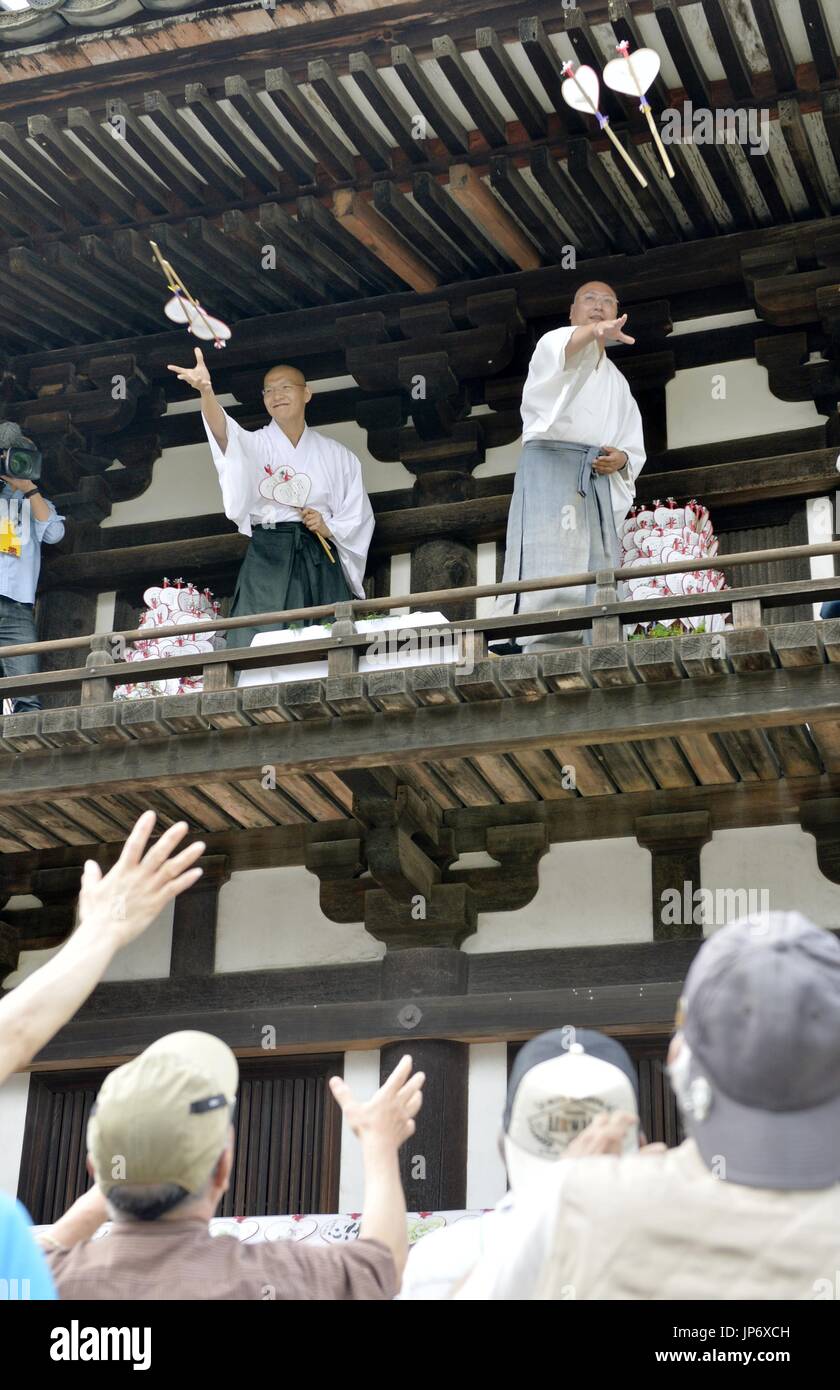 Buddhist monks distribute heart-shaped fans from the balcony of a drum ...