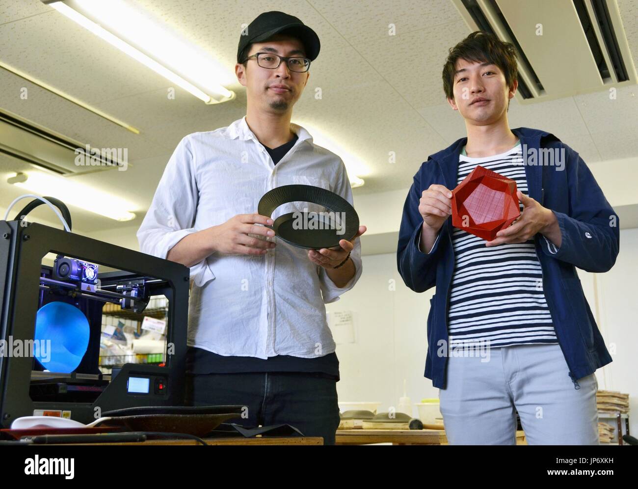 Designers Yuichi Yanai (L) and Tatsuya Uemachi hold newfangled ceramics made by a 3-D printer in ...