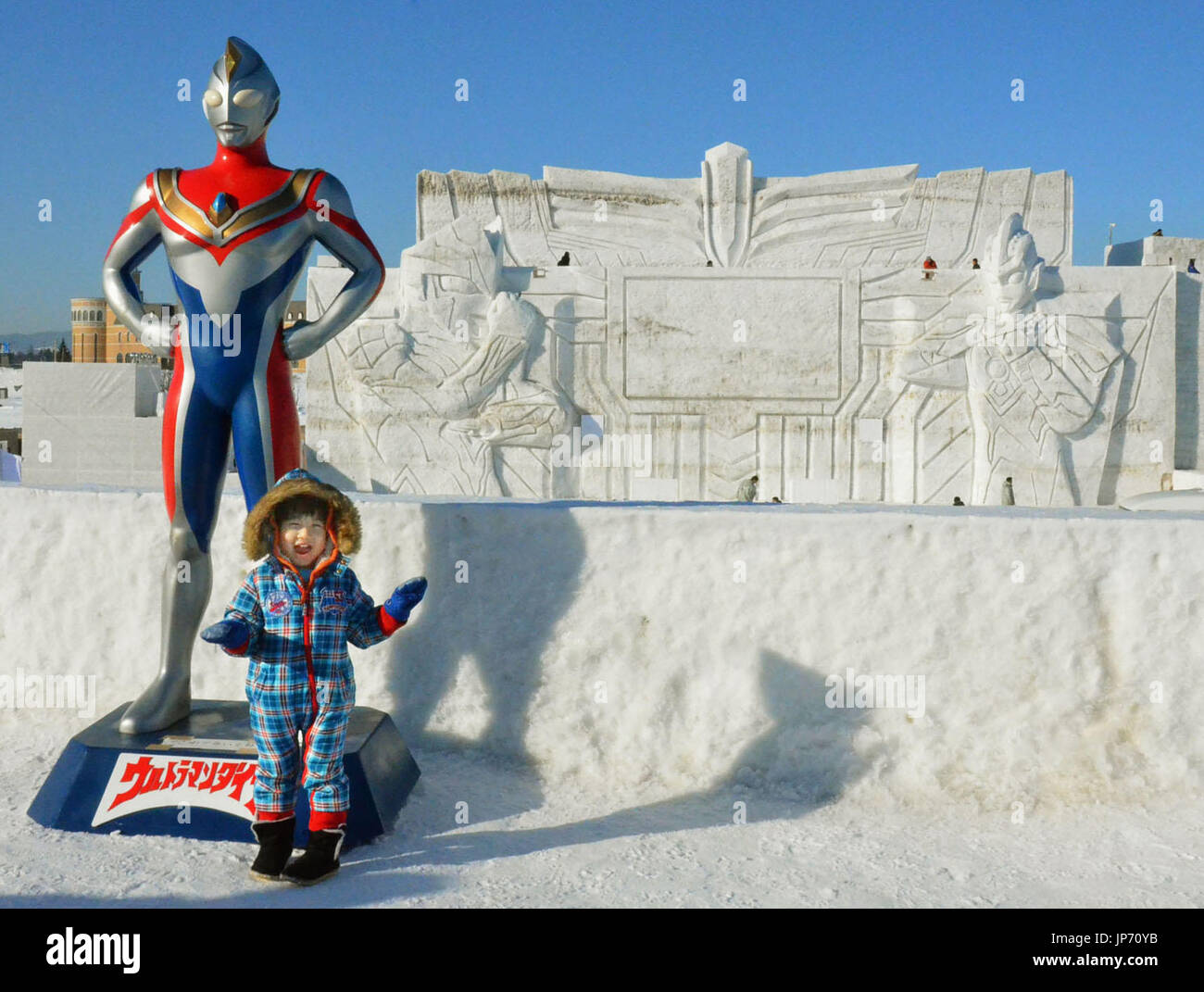 A child strikes a pose for a picture in front of a huge snow sculpture ...
