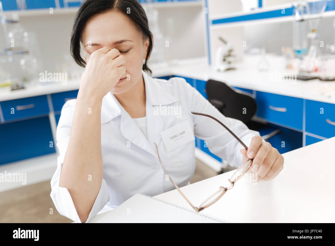 Tired female scientist sitting at the table Stock Photo - Alamy