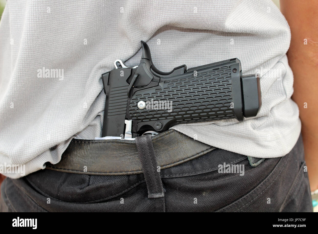 gangster concealing his gun behind his back Stock Photo - Alamy