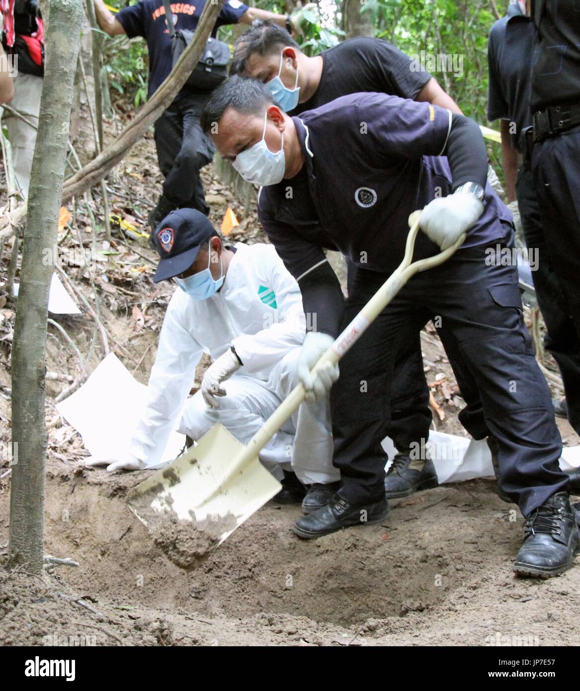 Investigators dig up bodies from a suspected mass grave on May 26, 2015 ...