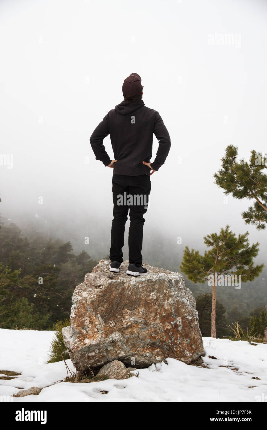 Handsome caucasian young man climbed up a rock in the mountain on a ...