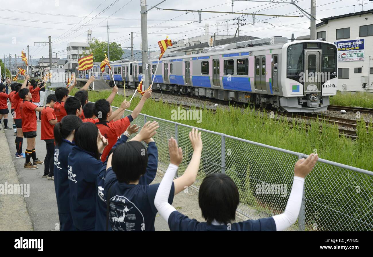 High school students wave to a train on the 47.2-km Senseki-Tohoku Line ...