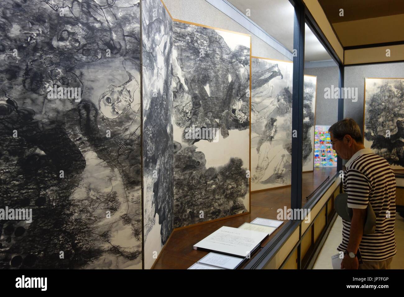 A visitor looks at one of 15 large folding-screen panels on the U.S ...