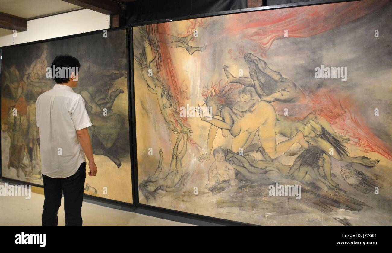A visitor looks at one of the nine paintings by Japanese artists Iri ...