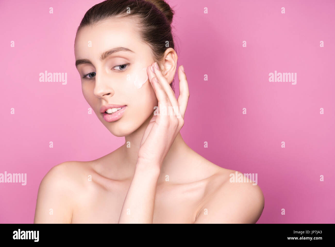 Portrait of beautiful model lady with natural make-up applying cream on ...