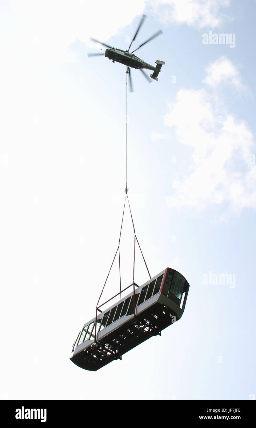A helicopter transports a new cable car on June 25, 2015, over Isehara ...