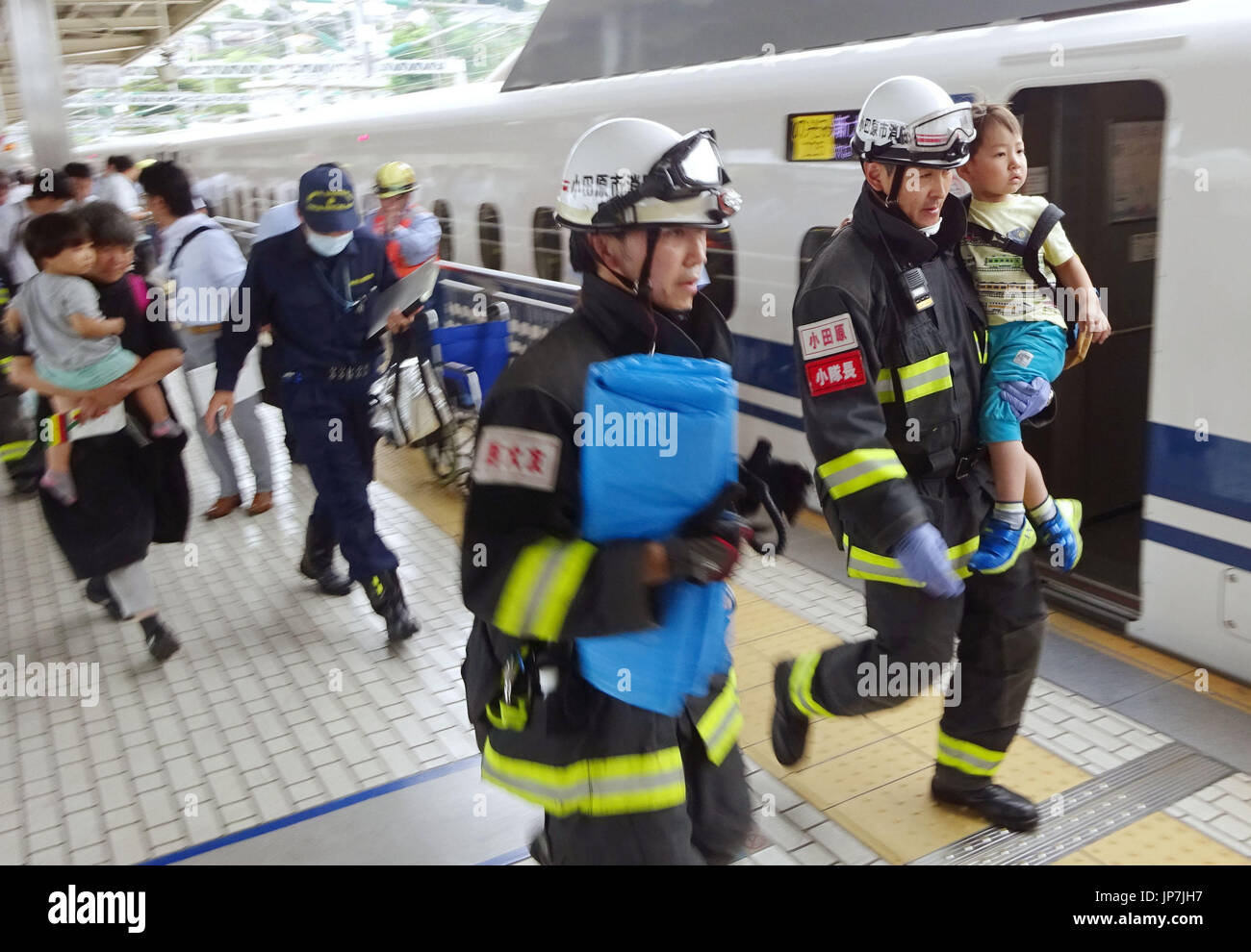 A firefighter carries a child from a shinkansen bullet train at Odawara ...