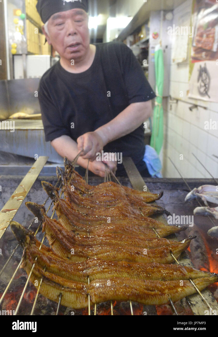 An eel restaurant chef broils skewered eels in the city of Osaka ...