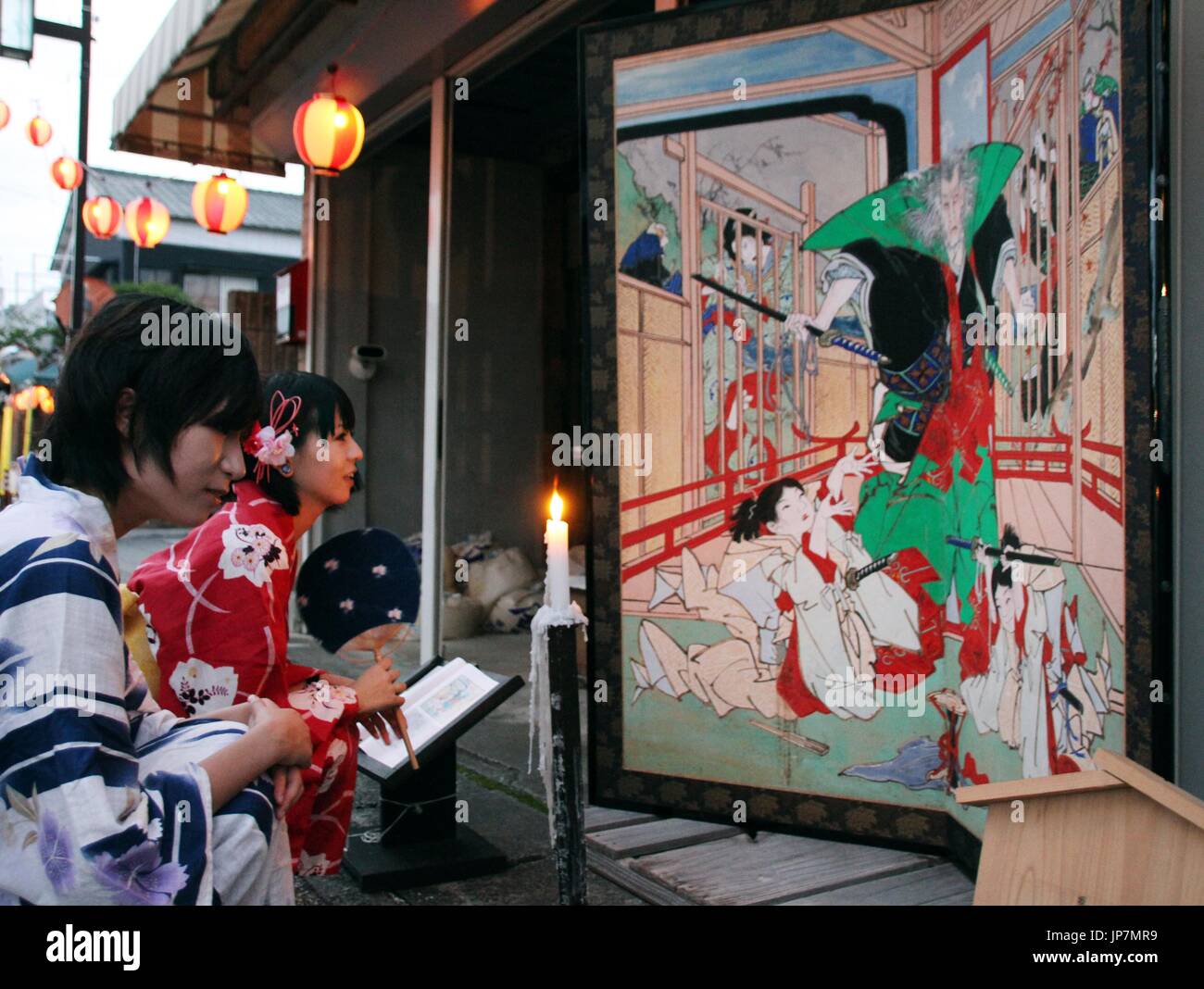 Young women clad in "yukata" summer kimono look at a folding screen ...