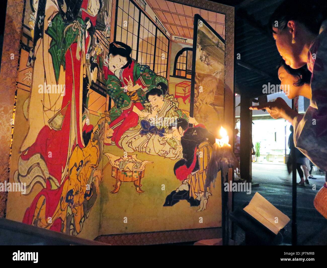People look at a folding screen painting hung under the eaves of a ...