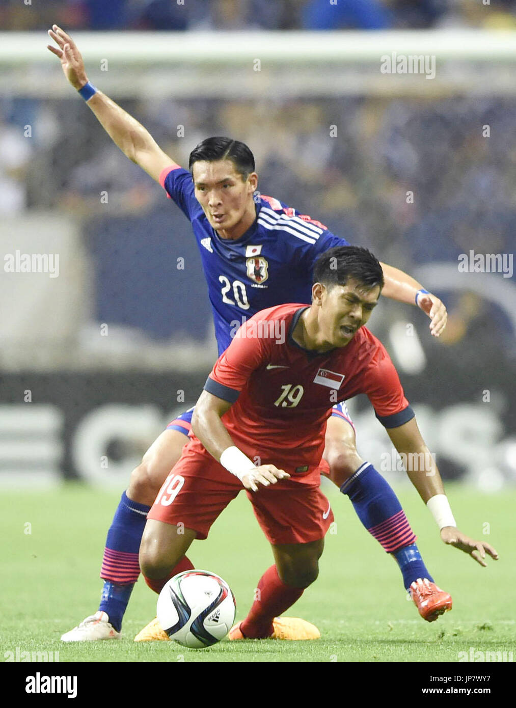 Tomoaki Makino of Japan (20) and Khairul Amri of Singapore (19) battle for the ball during the ...
