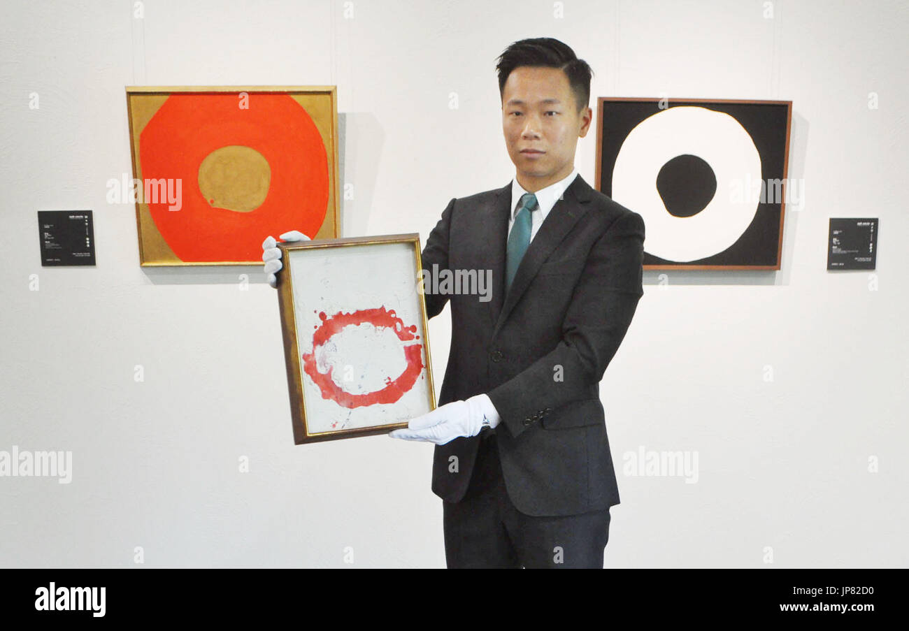 A man holds a painting by Japanese painter Jiro Yoshihara (1905-1972 ...