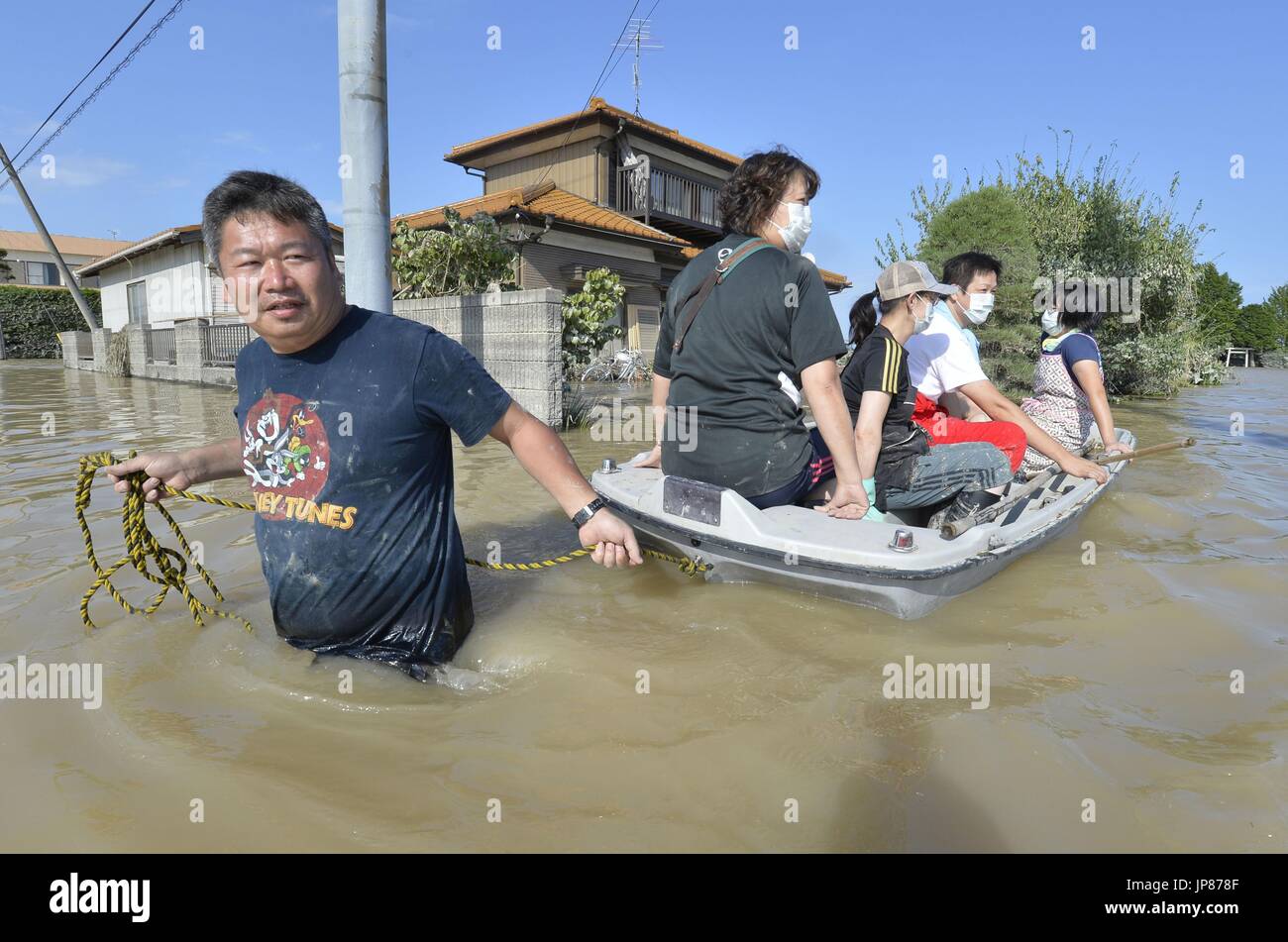 A man pulls a boat carrying family members through flood waters in a ...