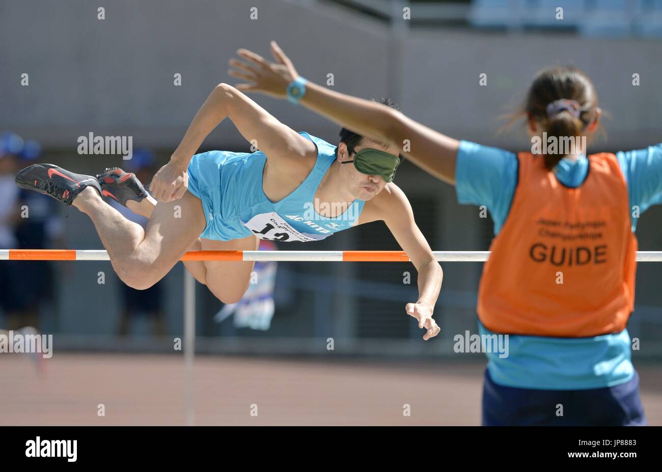 A visually impaired athlete takes a jump while listening to his guide's ...