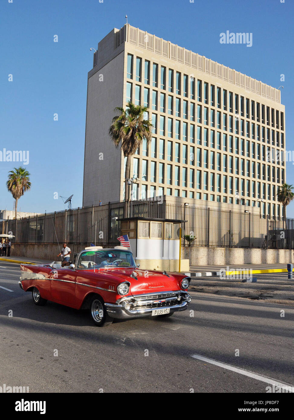 Photo shows a classic car with a U.S. flag driving besides the U.S ...