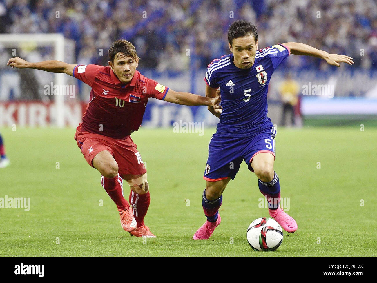 Sokumpheak Kouch of Cambodia (L) and Yuto Nagatomo vie for the ball ...