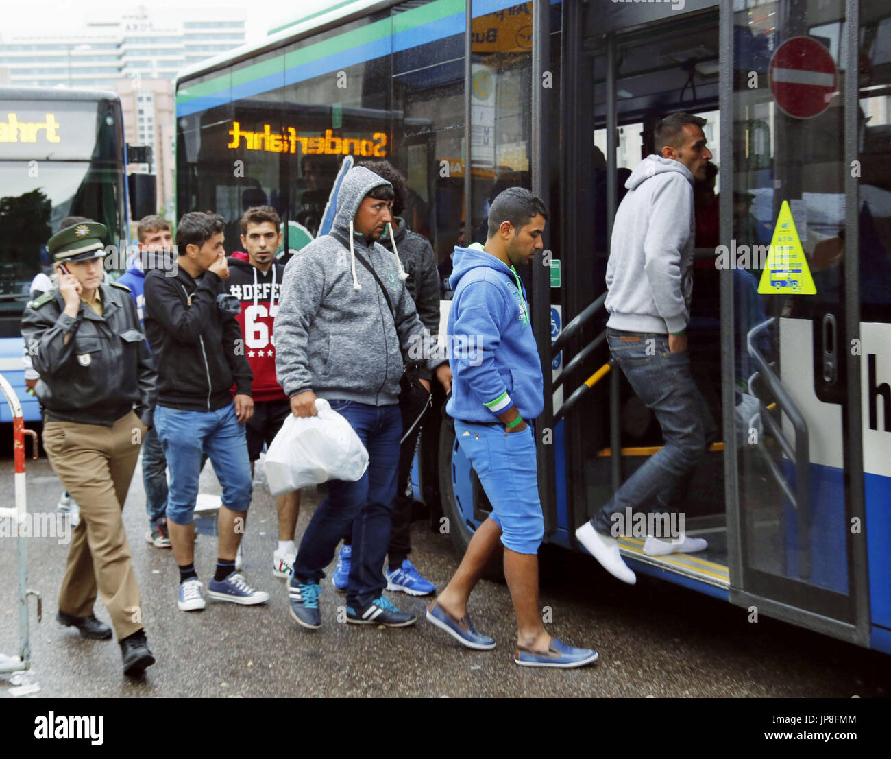 Refugees board buses after arriving at the central train station in ...