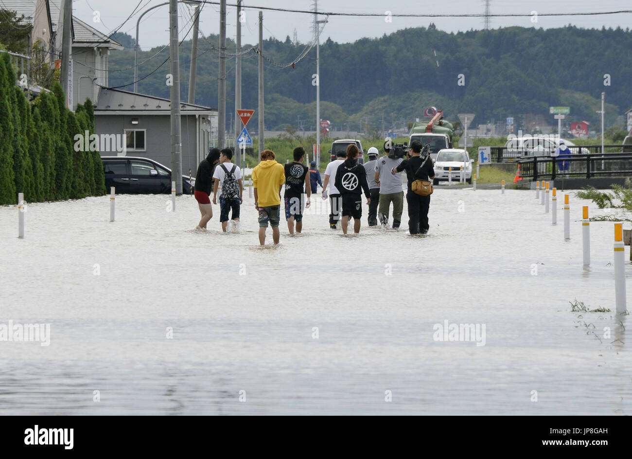 A group of people evacuate along an inundated street in Osaki ...