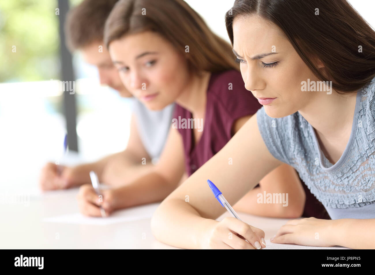 Student trying to copy an exam from another classmate at classroom ...