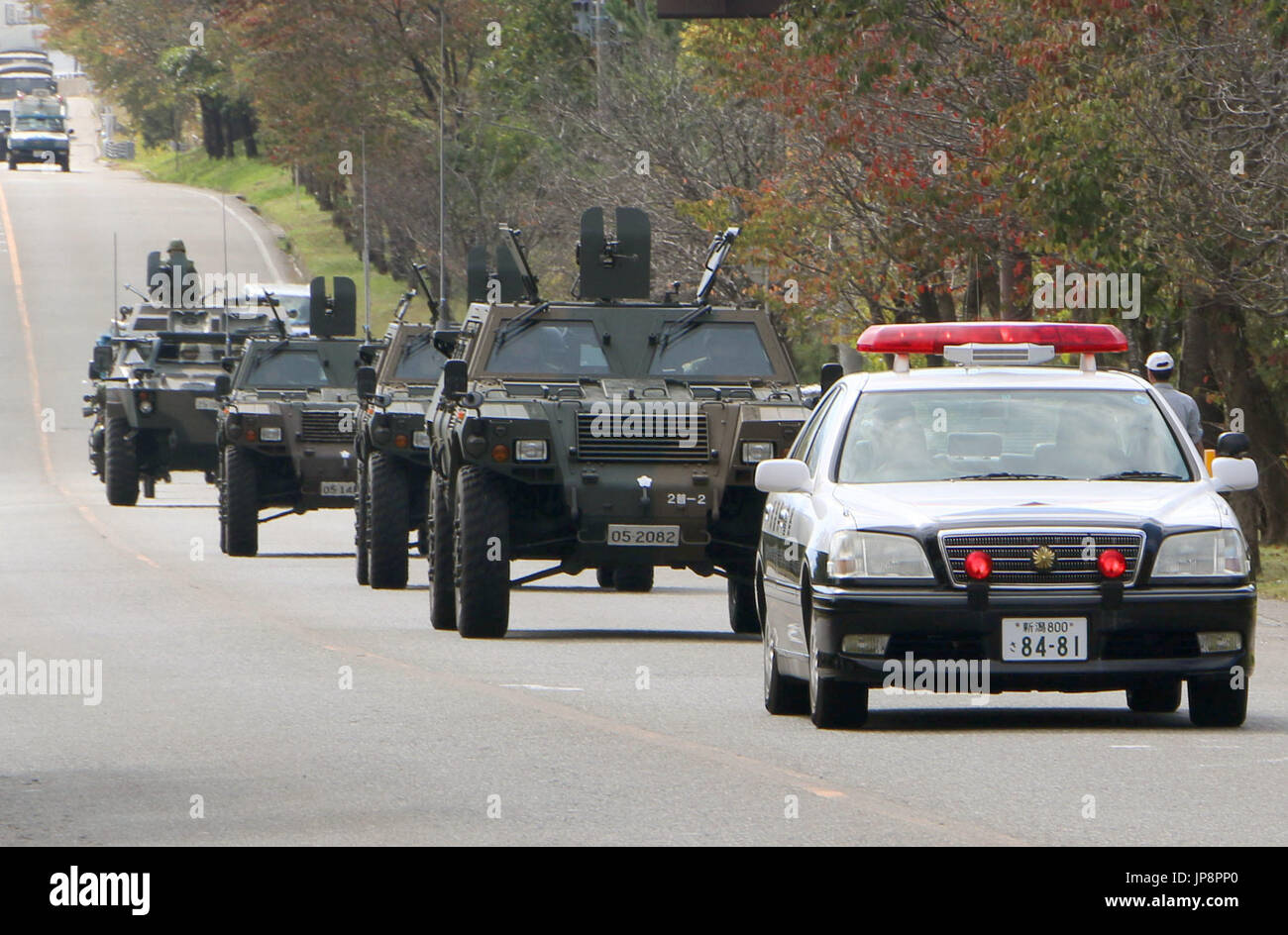 A police patrol car leads Japanese Ground Self-Defense Force vehicles ...