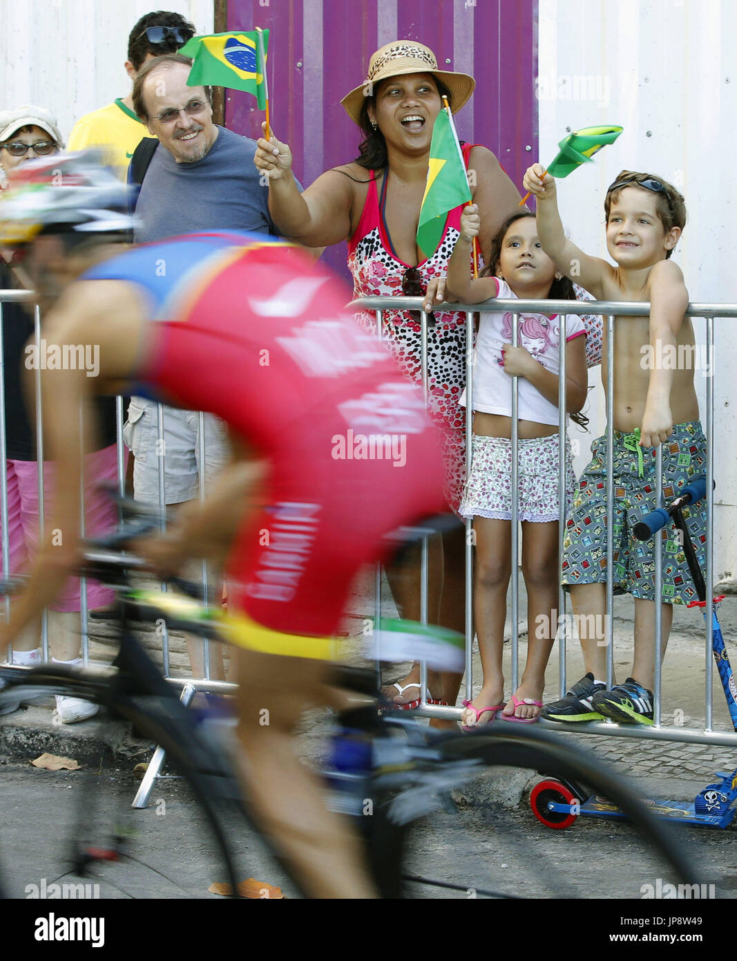 Flag-waving locals cheer along the roadside for triathletes during a ...