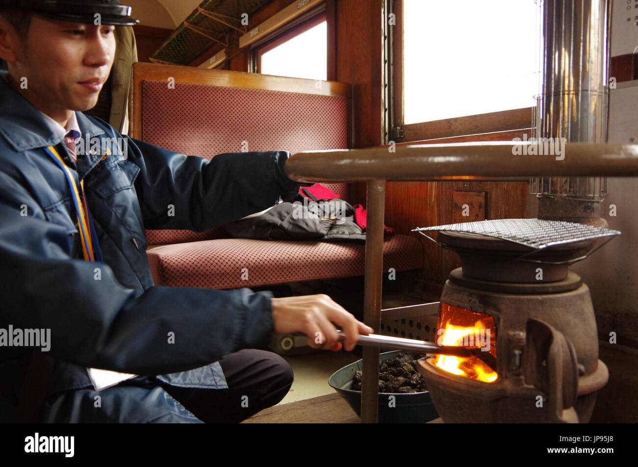 A conductor on Tsugaru Railway Co.'s "stove train" puts coal into a ...