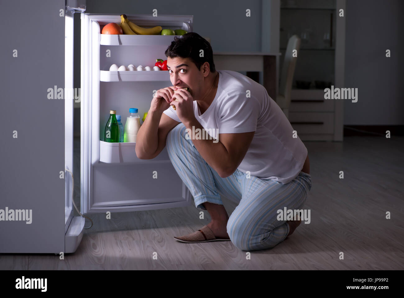Man at the fridge eating at night Stock Photo - Alamy