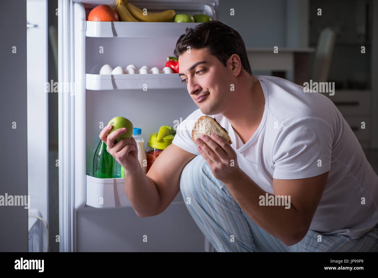 Man at the fridge eating at night Stock Photo - Alamy