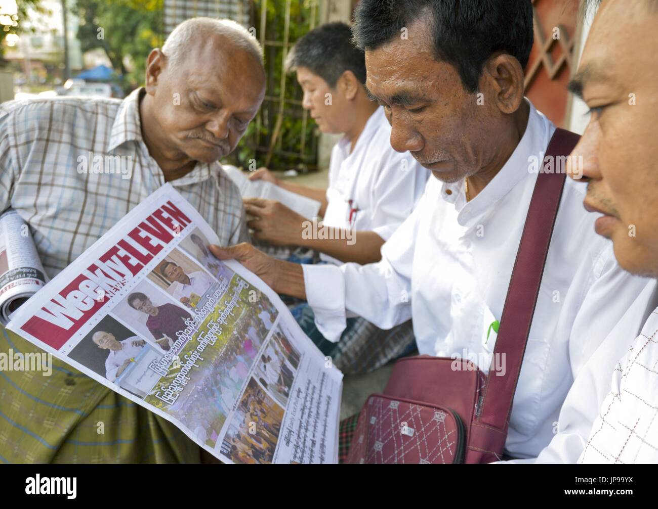 People read a newspaper reporting on Myanmar's first fully democratic ...