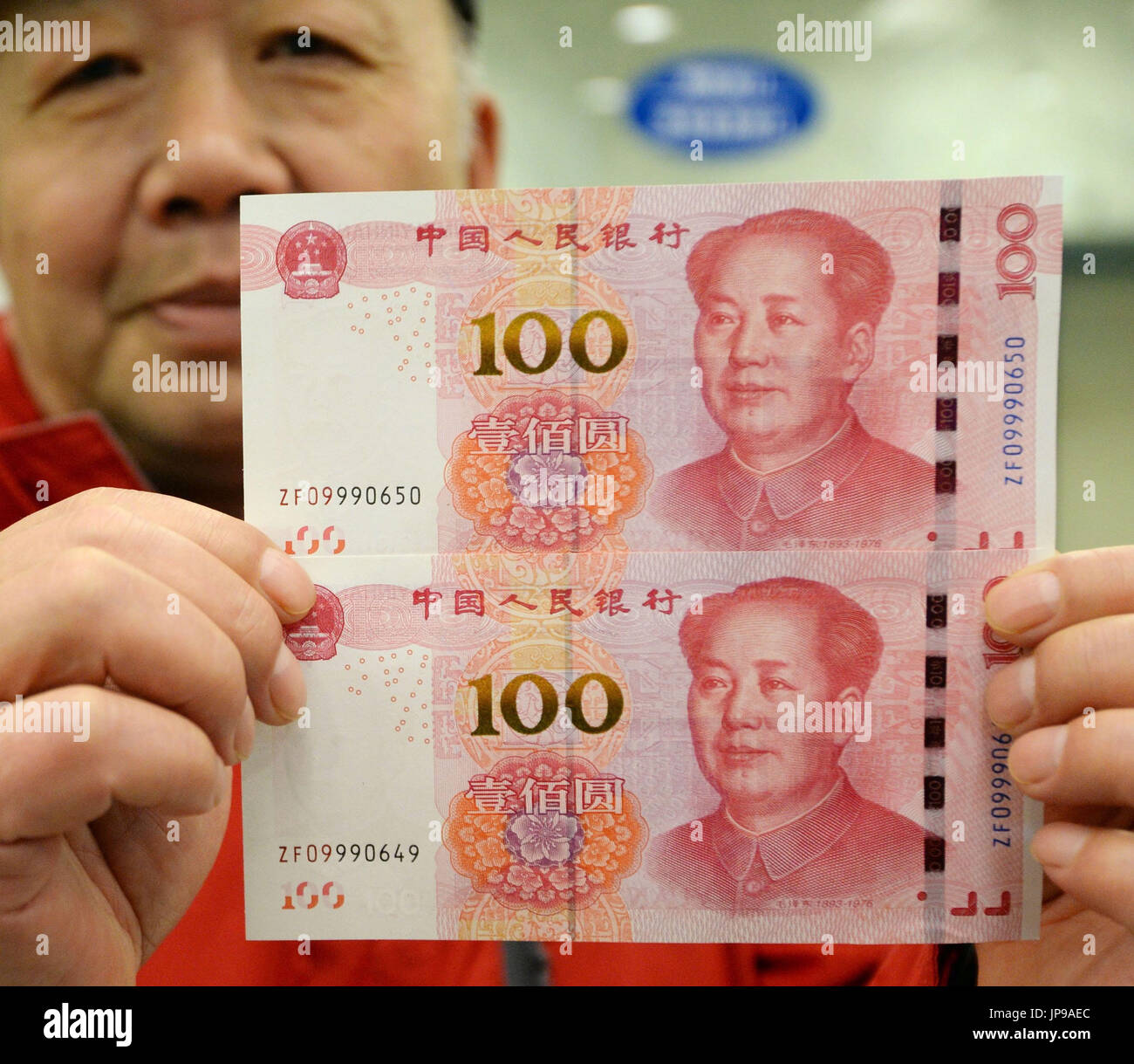 A man shows the new 100 yuan banknote which was issued on Nov. 12, 2015 ...