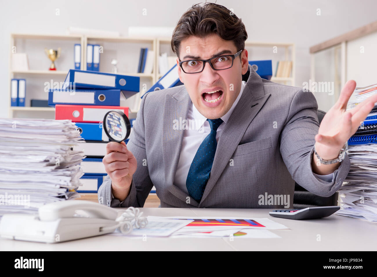 Male businessman with magnifying glass in office Stock Photo - Alamy