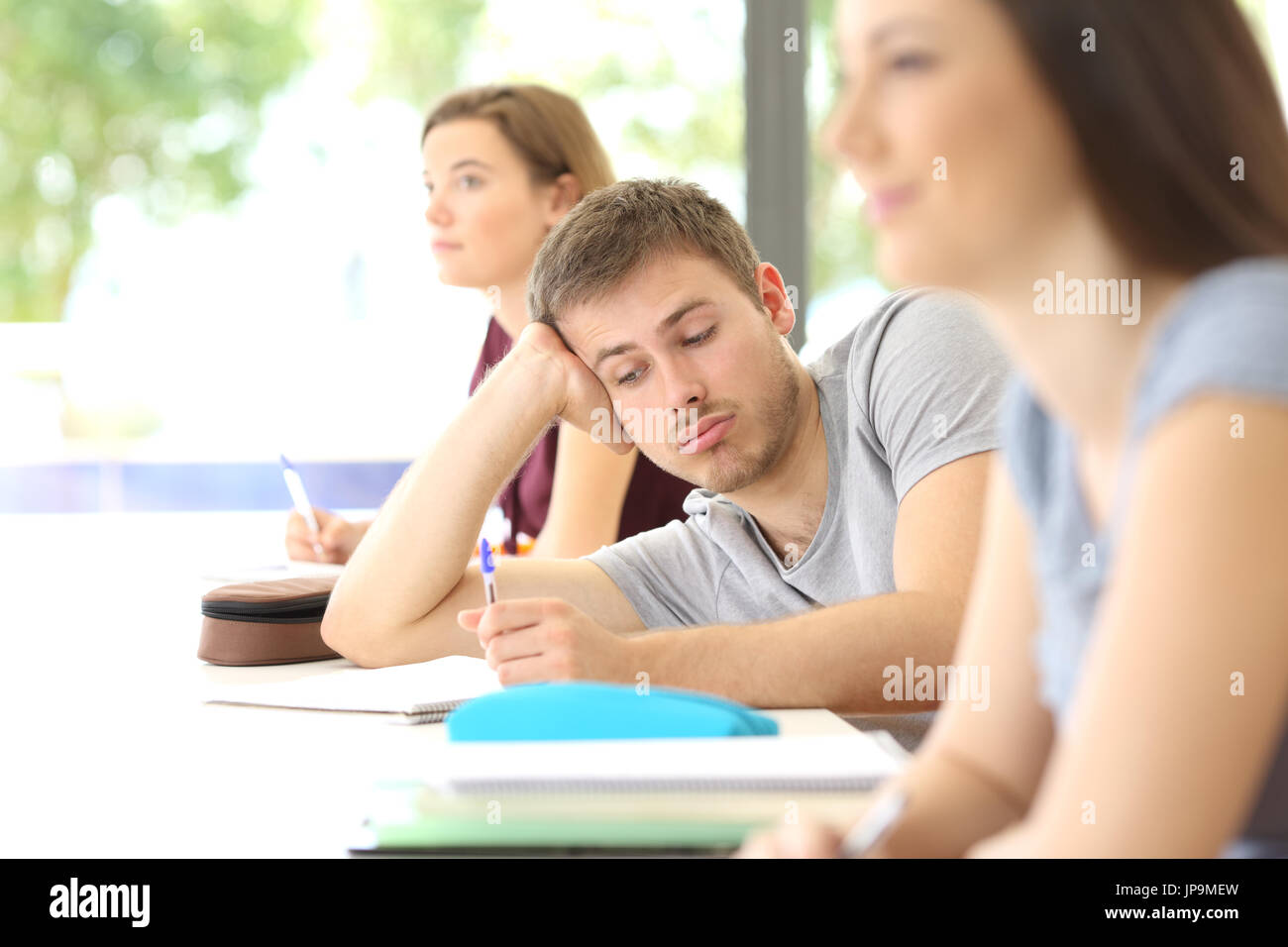 Bored student distracted during a class at classroom with classmates in ...