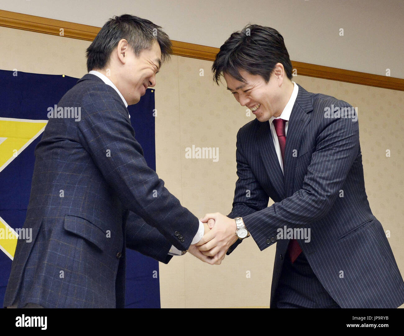 Osaka's new mayor Hirofumi Yoshimura (R) shakes hands with his predecessor Toru Hashimoto in ...