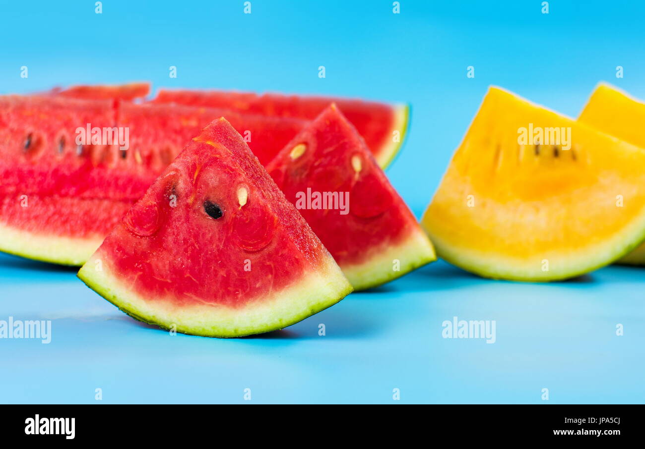 Yellow and red watermelon slices on blue background Stock Photo - Alamy