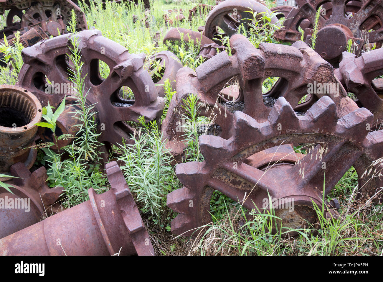 Rusting metal wheels in field of heavy equipment junkyard Stock Photo - Alamy