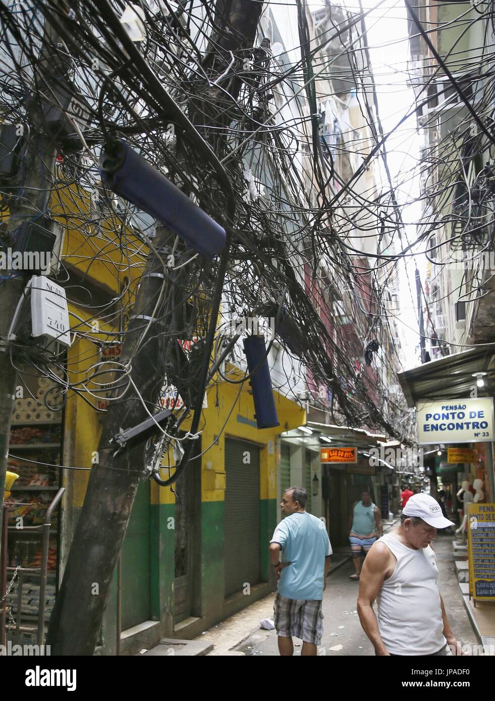 People walk under tangled electric cables in Rio de Janeiro's Rocinha ...