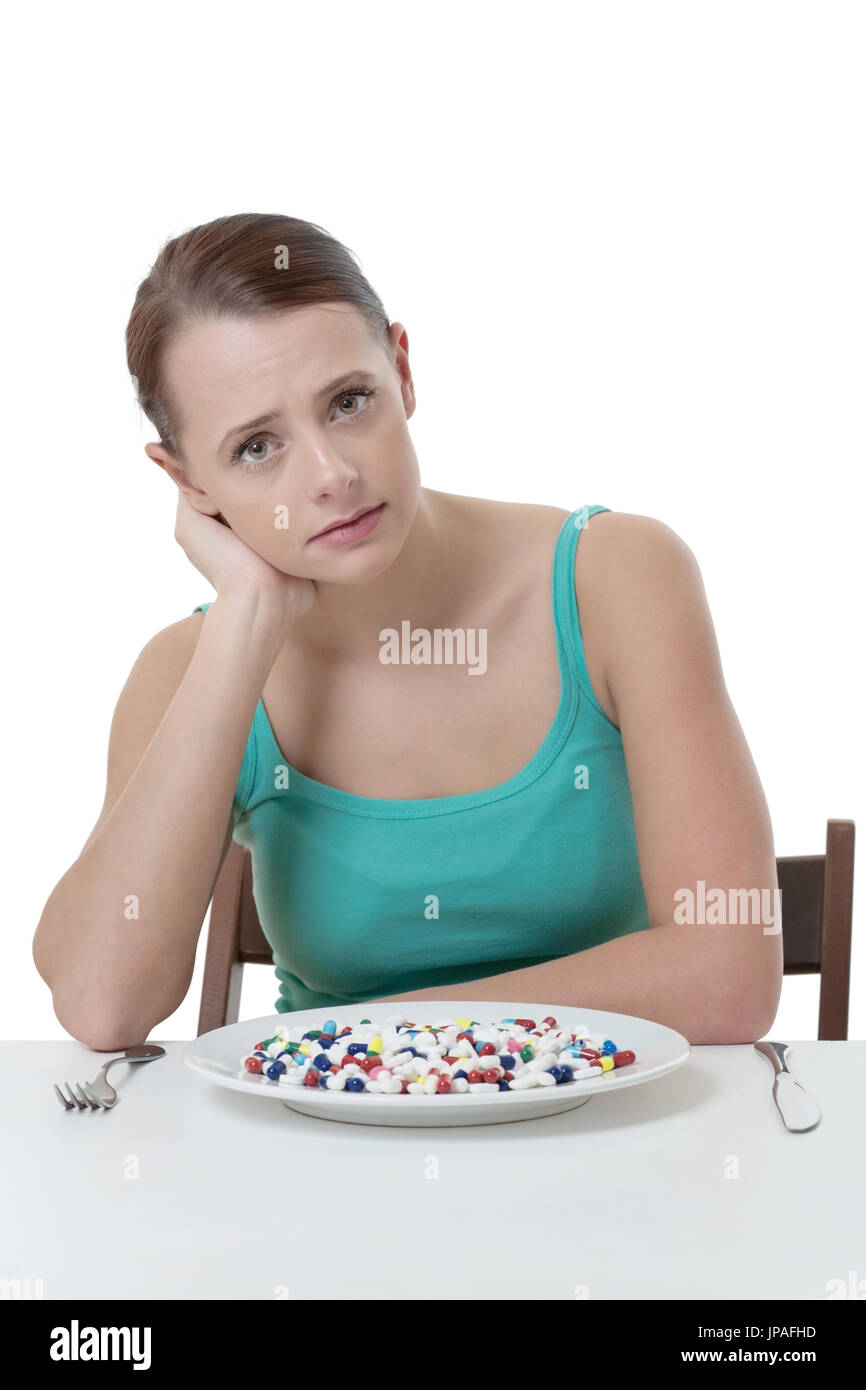 woman sitting at a tablet about to eat a plate full of tablets Stock ...