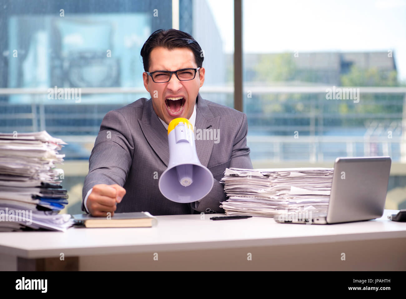 Angry businessman with loudspeaker in the office Stock Photo - Alamy