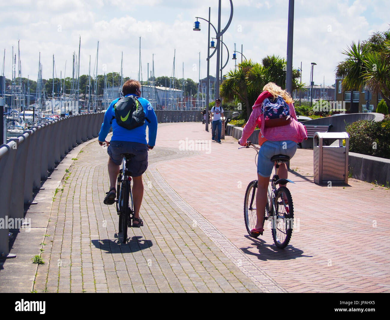 Two people ride their bicycles along the millennium promenade in ...