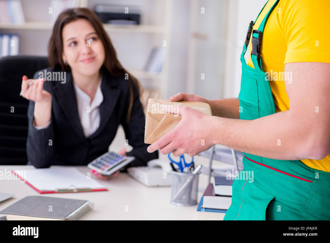 Postman delivering parcel to the office Stock Photo - Alamy
